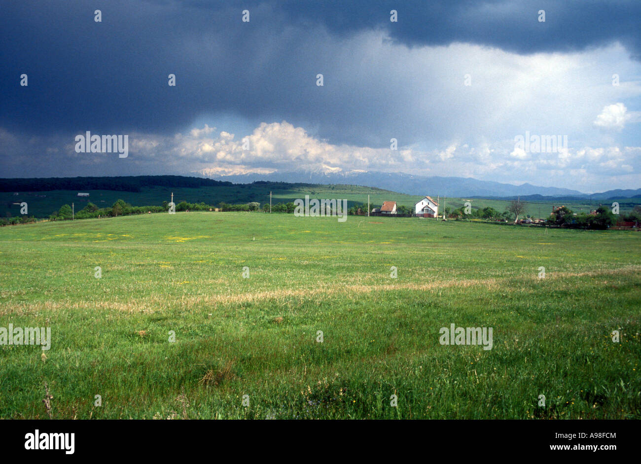 A dramatic Transylvanian landscape with hills, a farmhous and storm ...