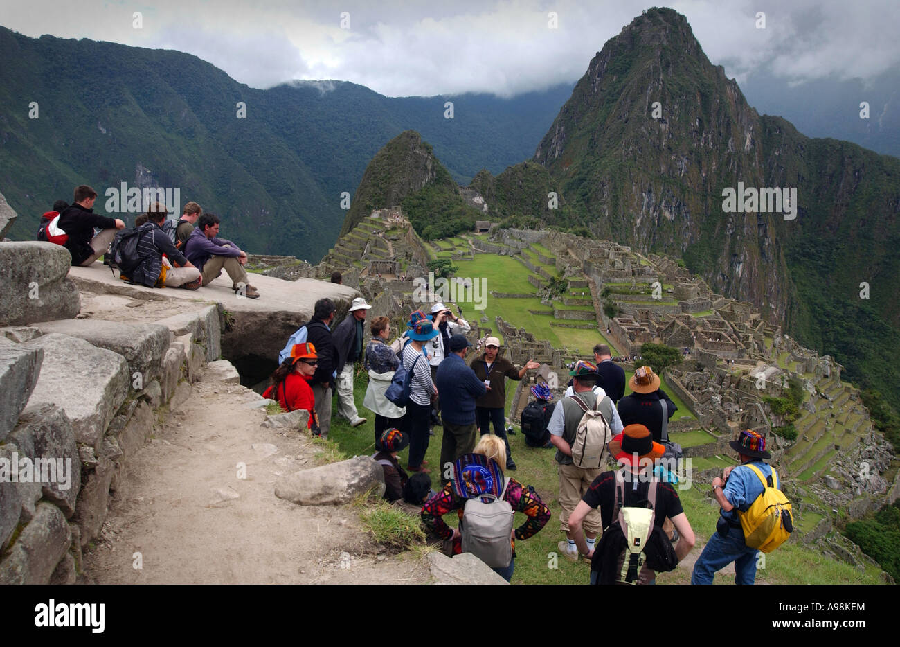 a tour guide talking to a group of tourists on a visit to Machu Picchu ...