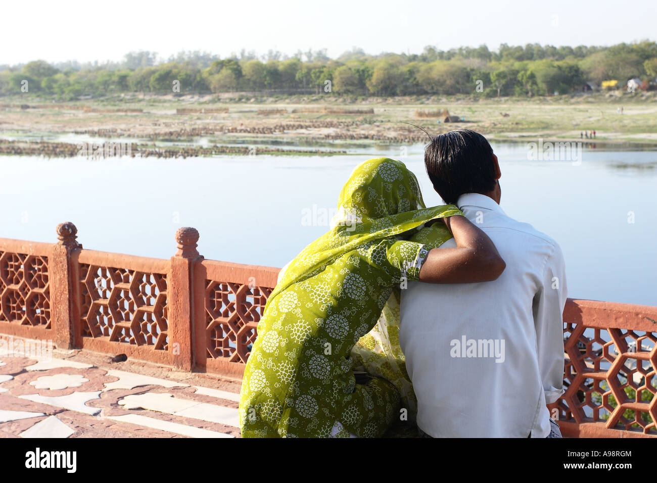 A couple sitting looking over the river from the Taj Mahal Stock Photo ...