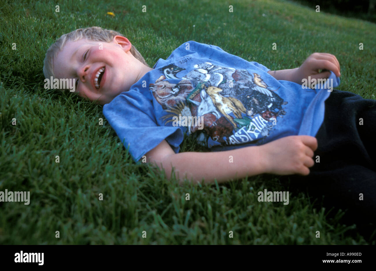 A boy laughing lying on grass Stock Photo - Alamy