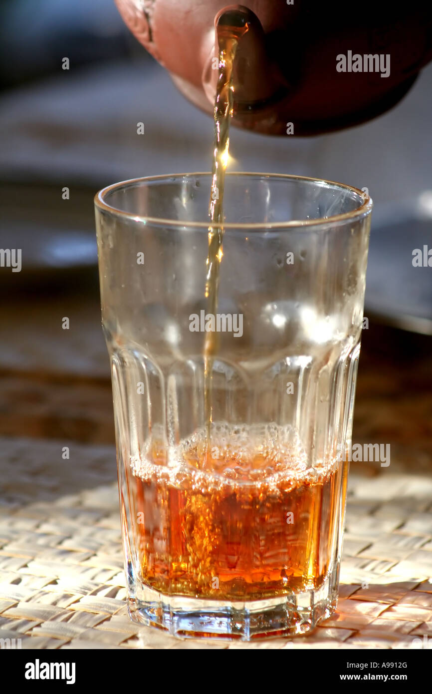 Pouring amber tea into a clear glass, highlighting the beverage's warm ...