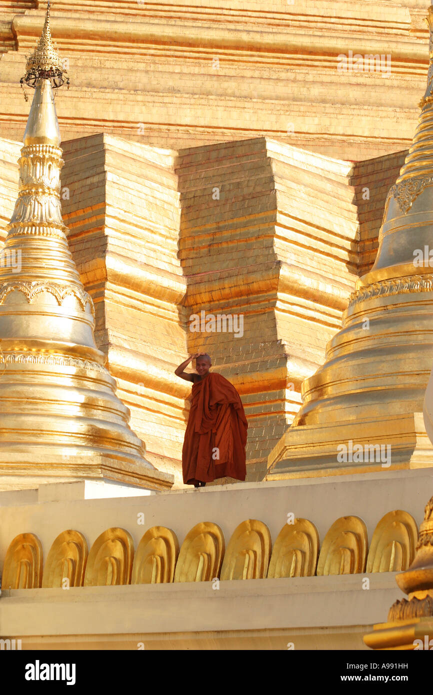 Red robed monk surrounded by golden spires of the dramatic Shwedagon ...