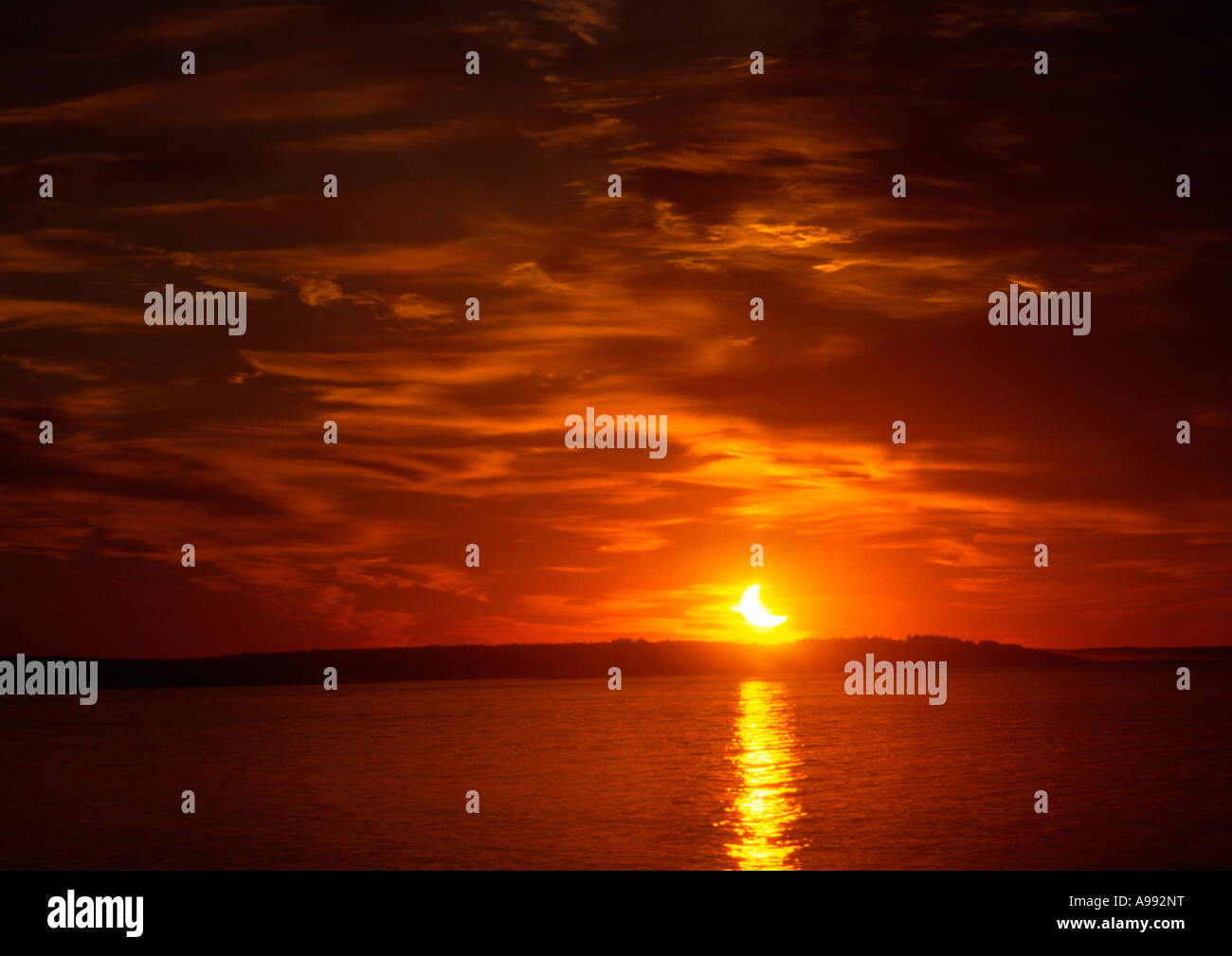 eclipse of the sun at sunrise over water Stock Photo - Alamy
