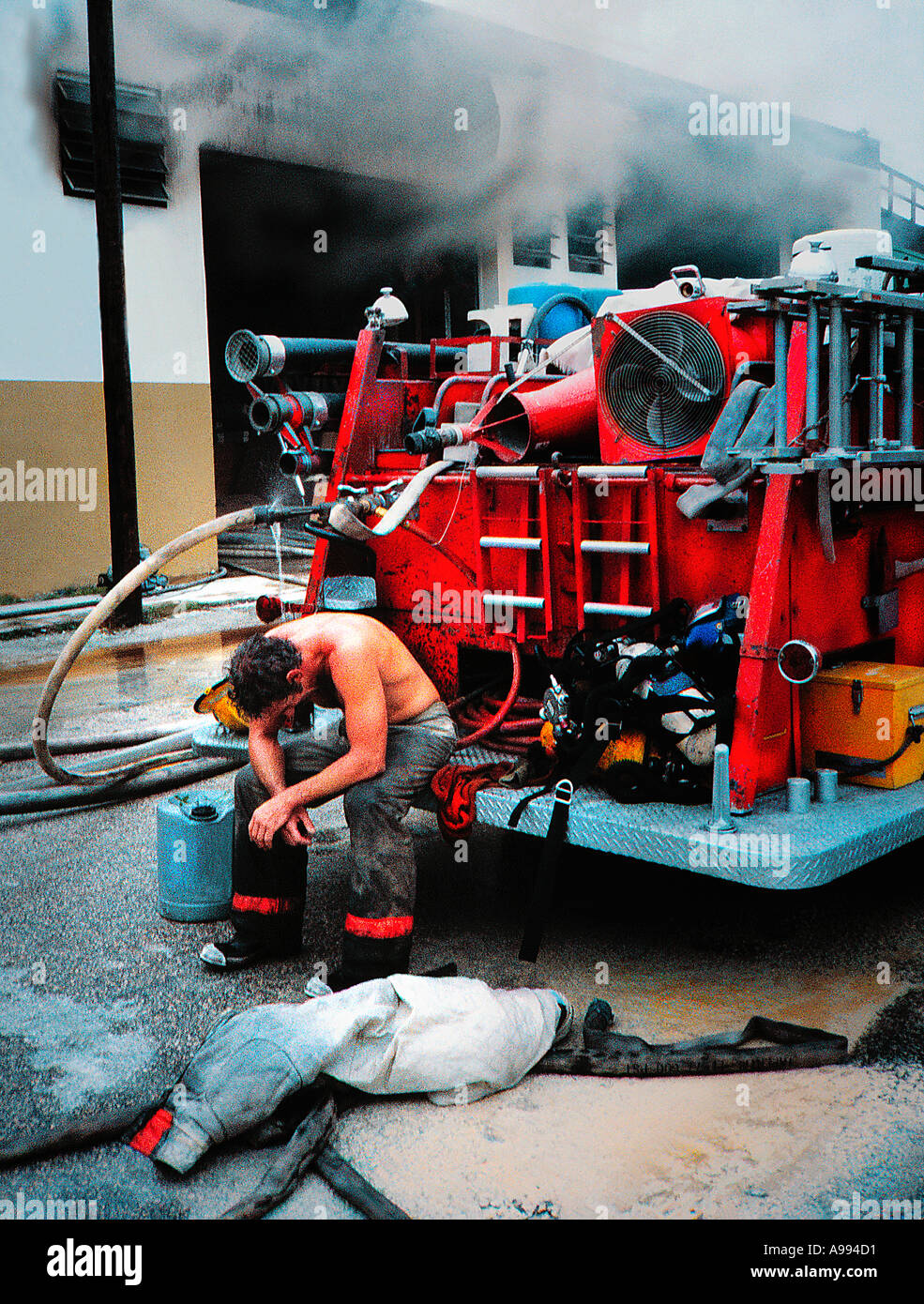 An exhausted fireman sits slumped over behind a fire truck outside a ...