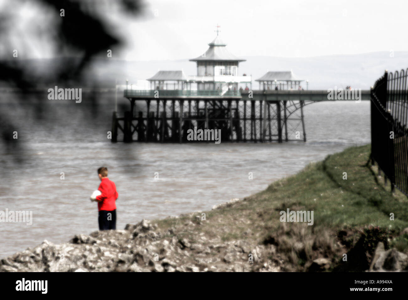 Boy in a red top with a football on the shoreline at Clevedon, Somerset ...