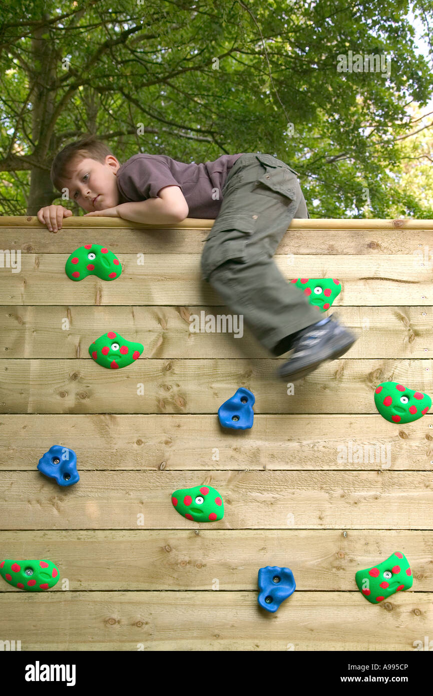 Young boy going over the top of a garden rock climbing wall Motion blur ...
