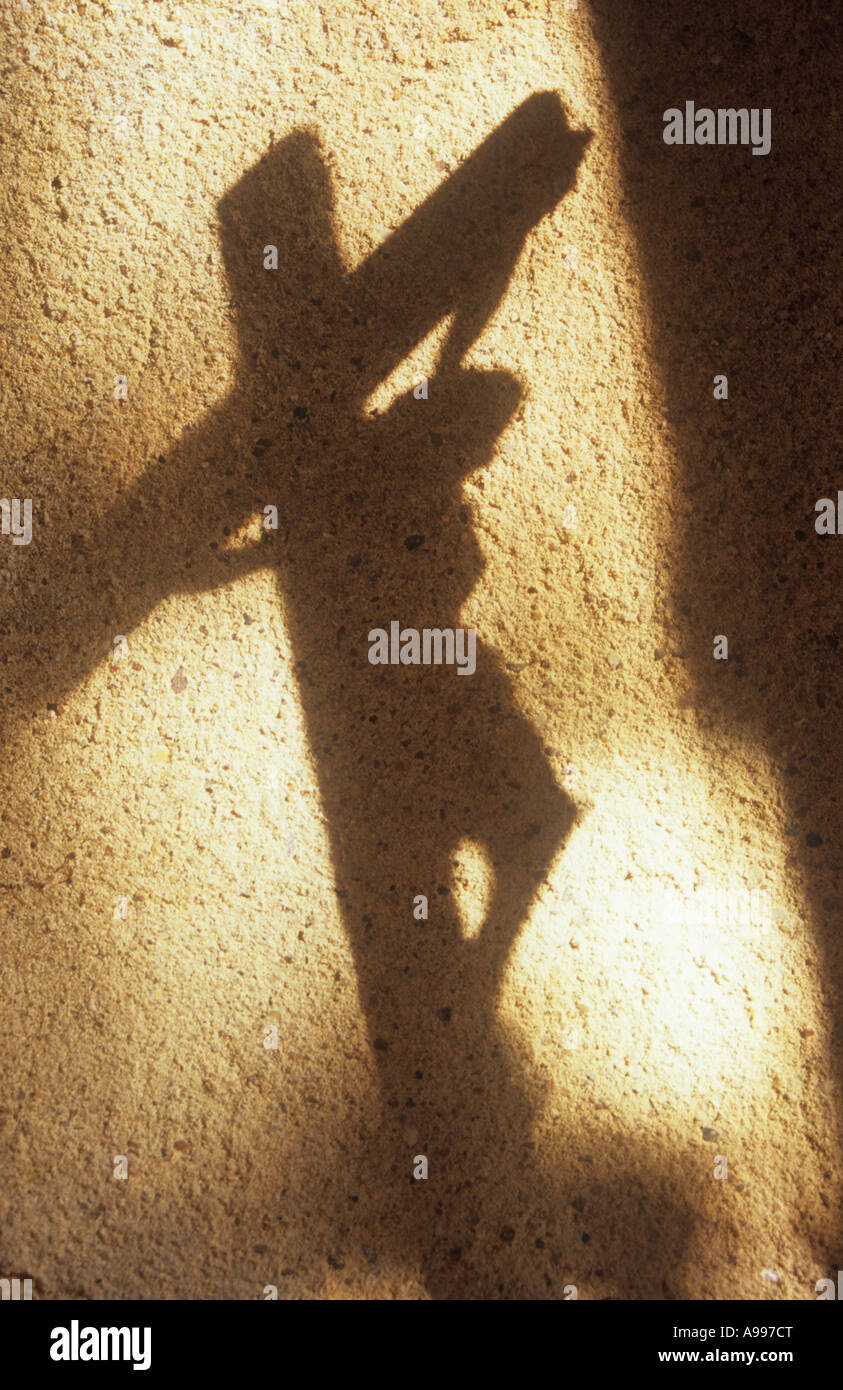 Shadow against a pale rendered wall of Jesus Christ hanging from a ...