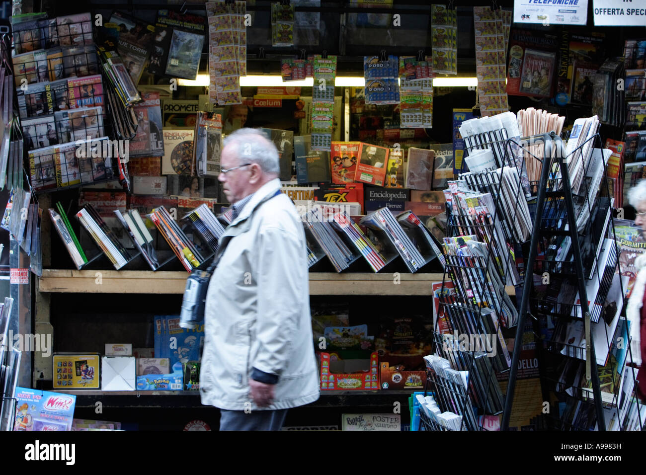 Pedestrian walks past a newsstand selling magazines and newspapers in ...