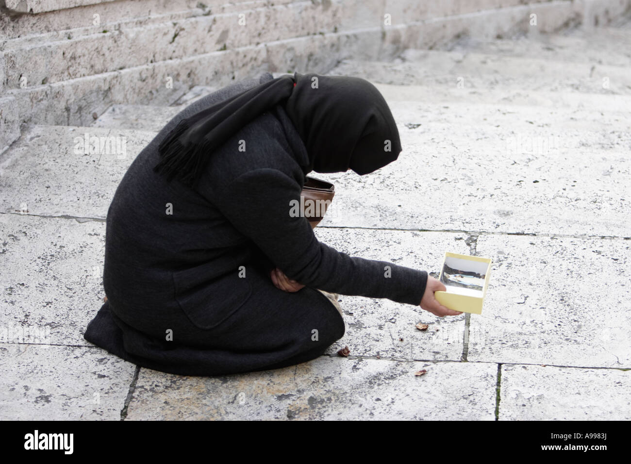 A beggar woman sits on the pavement at the Piazza di Spagna in Rome ...