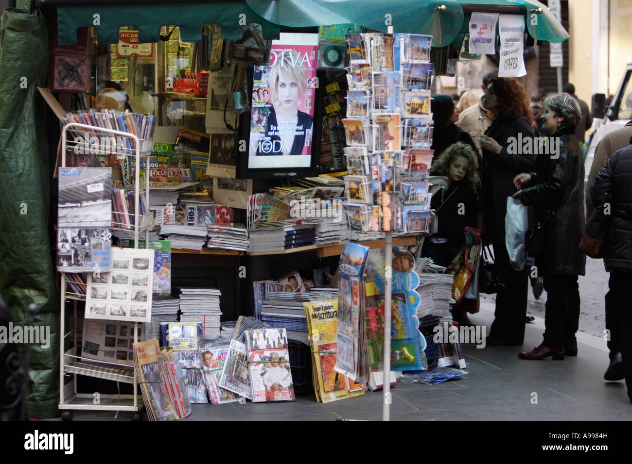 Pedestrians stand at a newsstand selling newspapers in downtown Rome ...