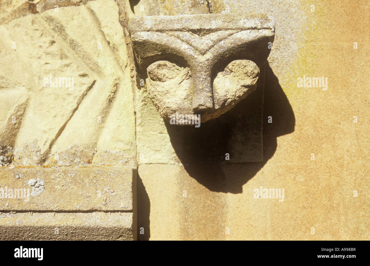 Detail of Norman stone archway with worn carved corbel of symbolic head ...