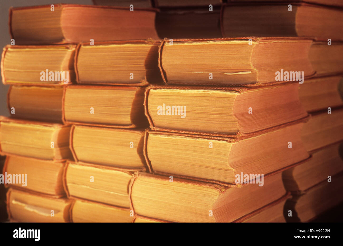 Stacks of well-thumbed books with red covers and edges in warm sunlight ...