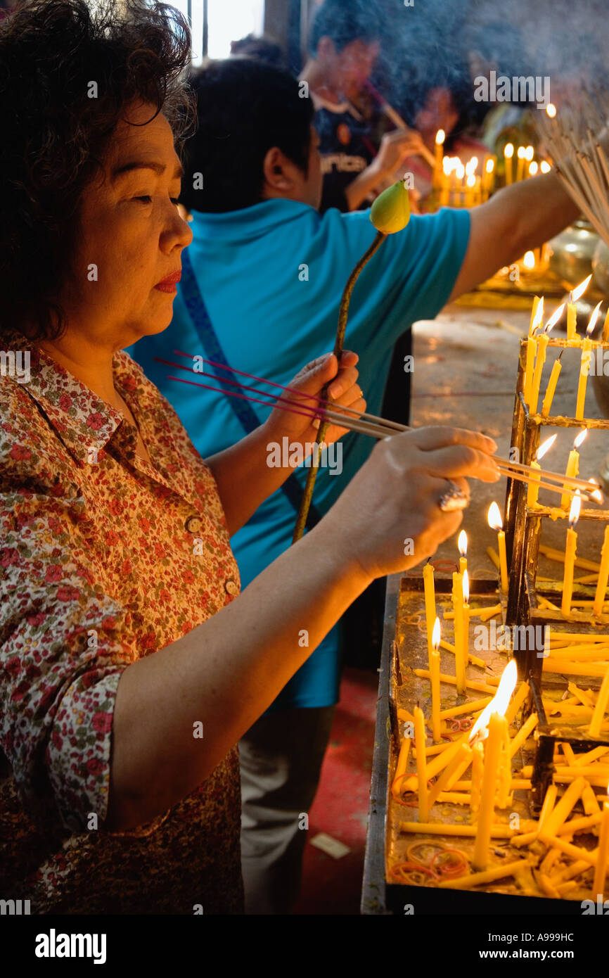 Buddhist pilgrim making her offerings to the Buddha by lighting her ...
