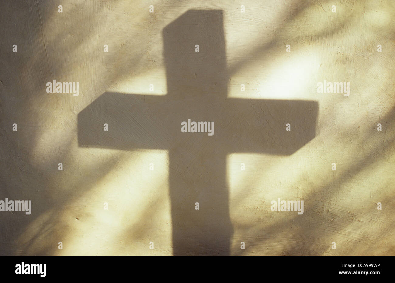 Shadow of crucifix cast onto cream painted rough wall with projection ...