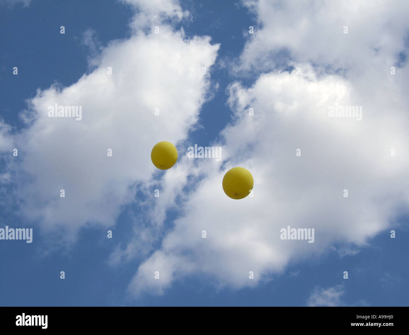 yellow balloons floating in blue sky Stock Photo - Alamy
