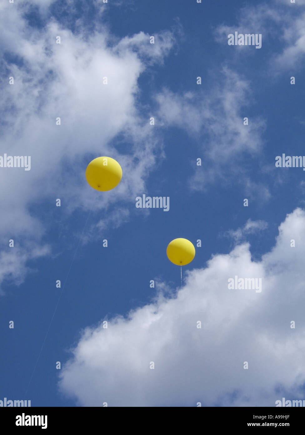 yellow balloons floating in blue sky Stock Photo - Alamy