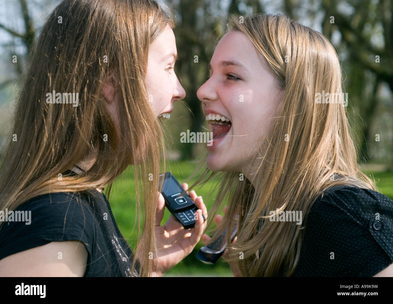 Two girls using mobile phones Stock Photo - Alamy