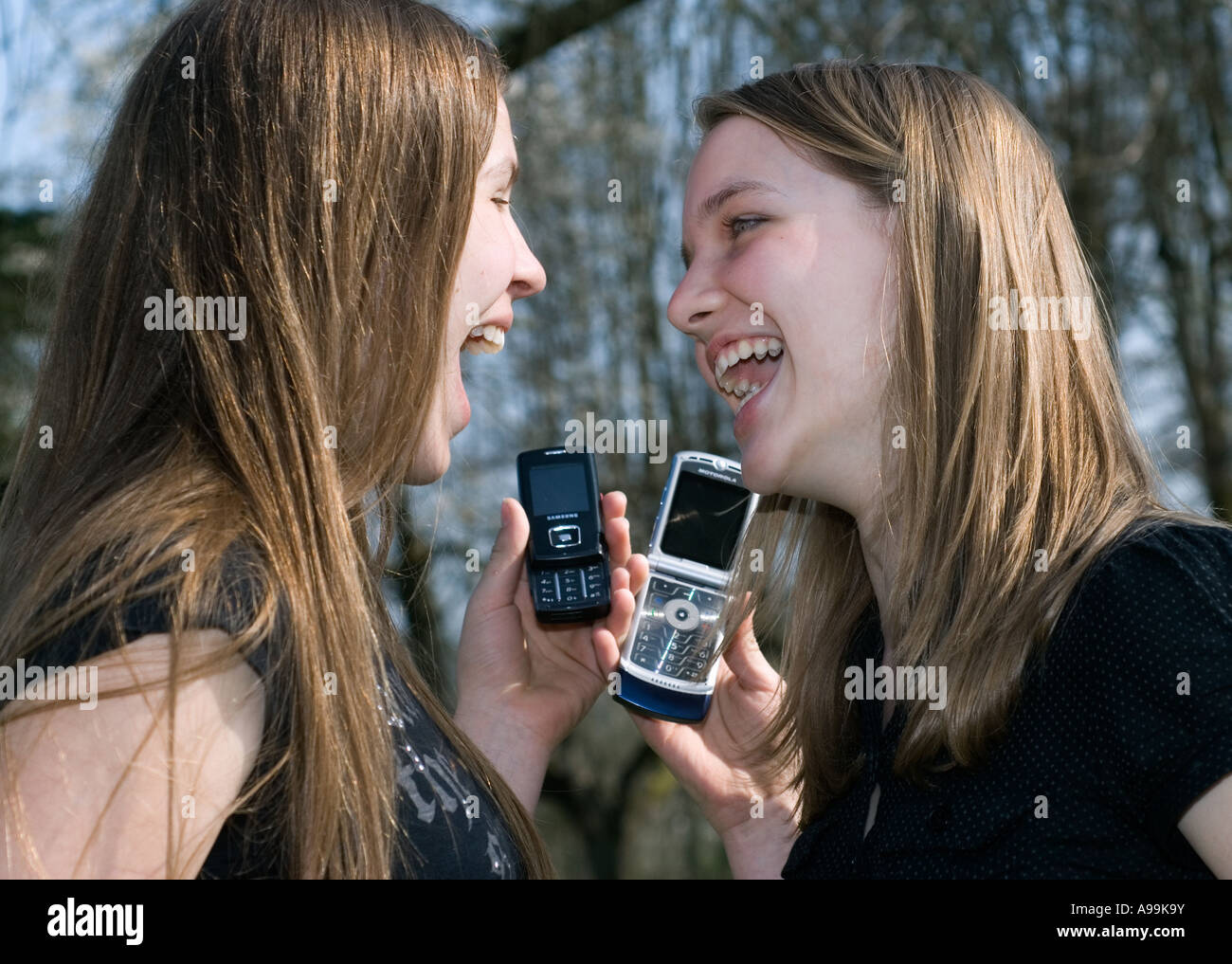 Two girls using mobile phones Stock Photo - Alamy