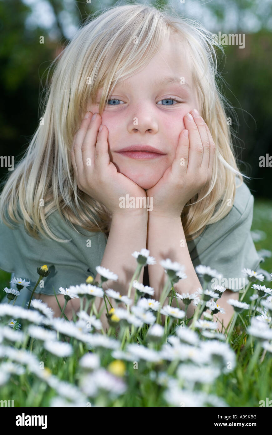7 year old girl lying on grass with daisy Stock Photo - Alamy
