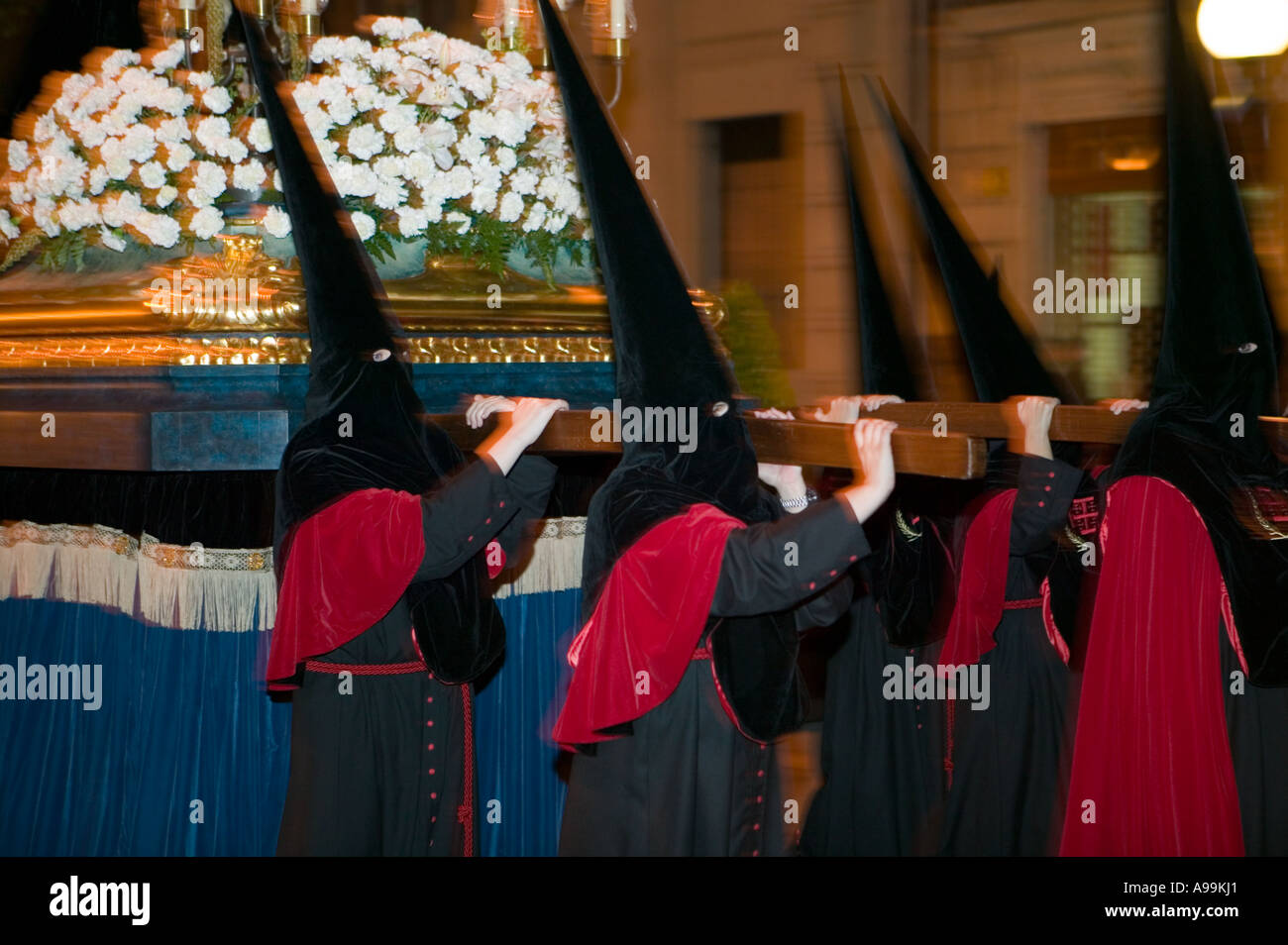 Members of a fraternity wearing tall peaked hoods carry a float during ...
