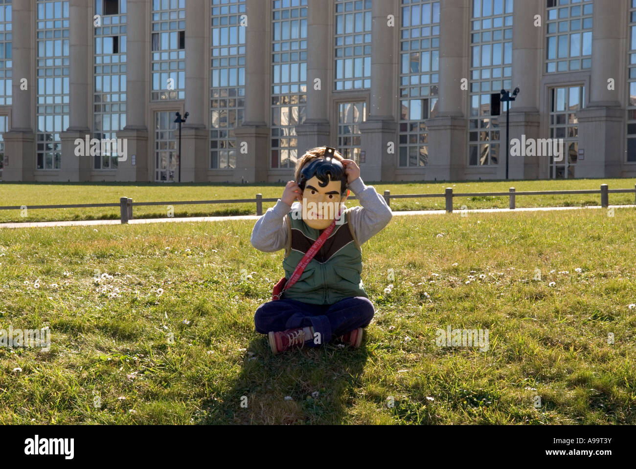 A close up of a child with superman mask sitting on grass in front of ...