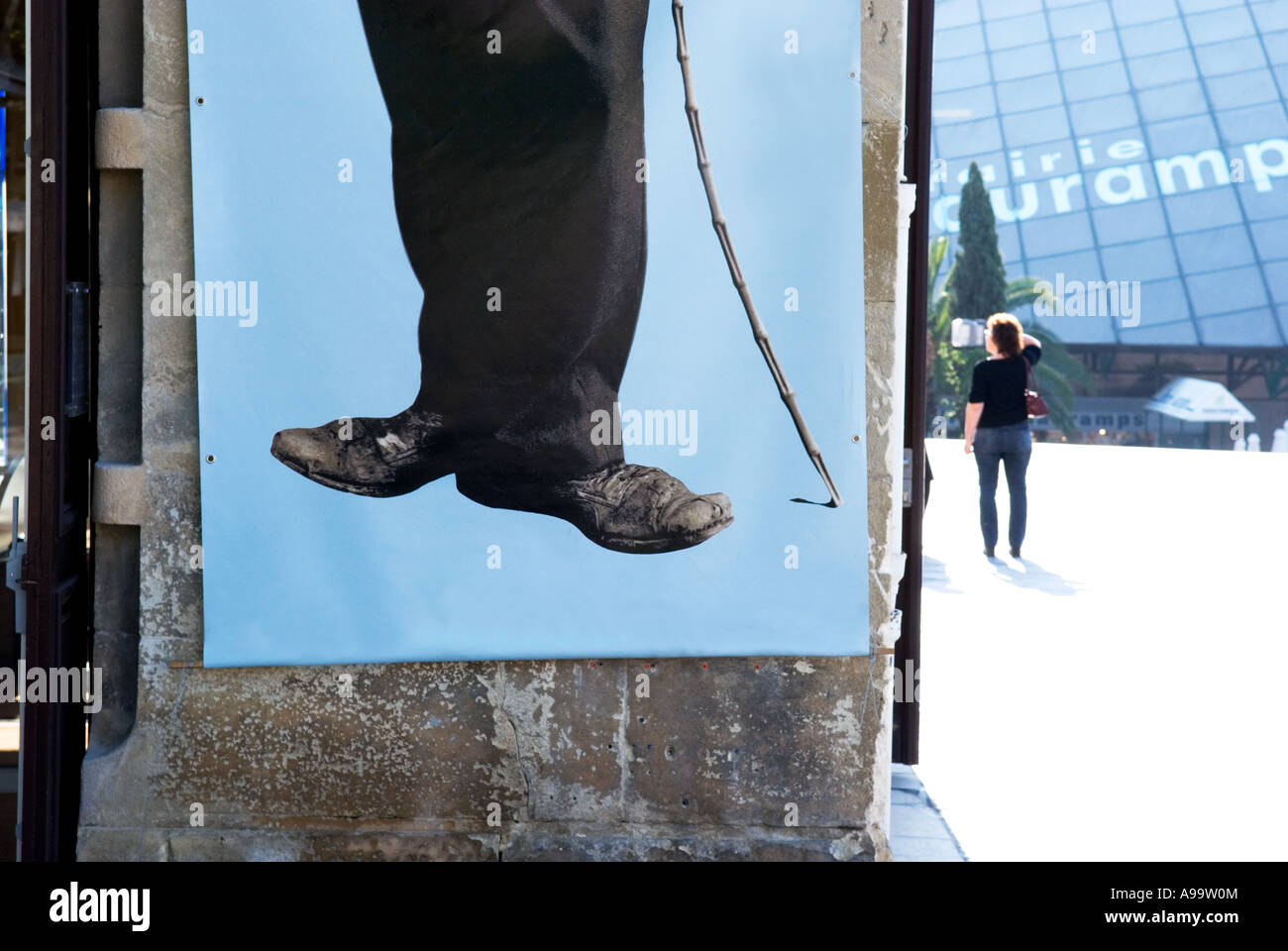 A Cropped View Of Charlie Chaplins Feet On A Poster With A Person In A Public Square In The