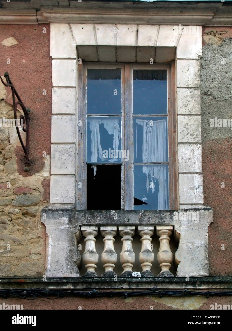 ripped curtains at a broken window of an empty left house in France ...