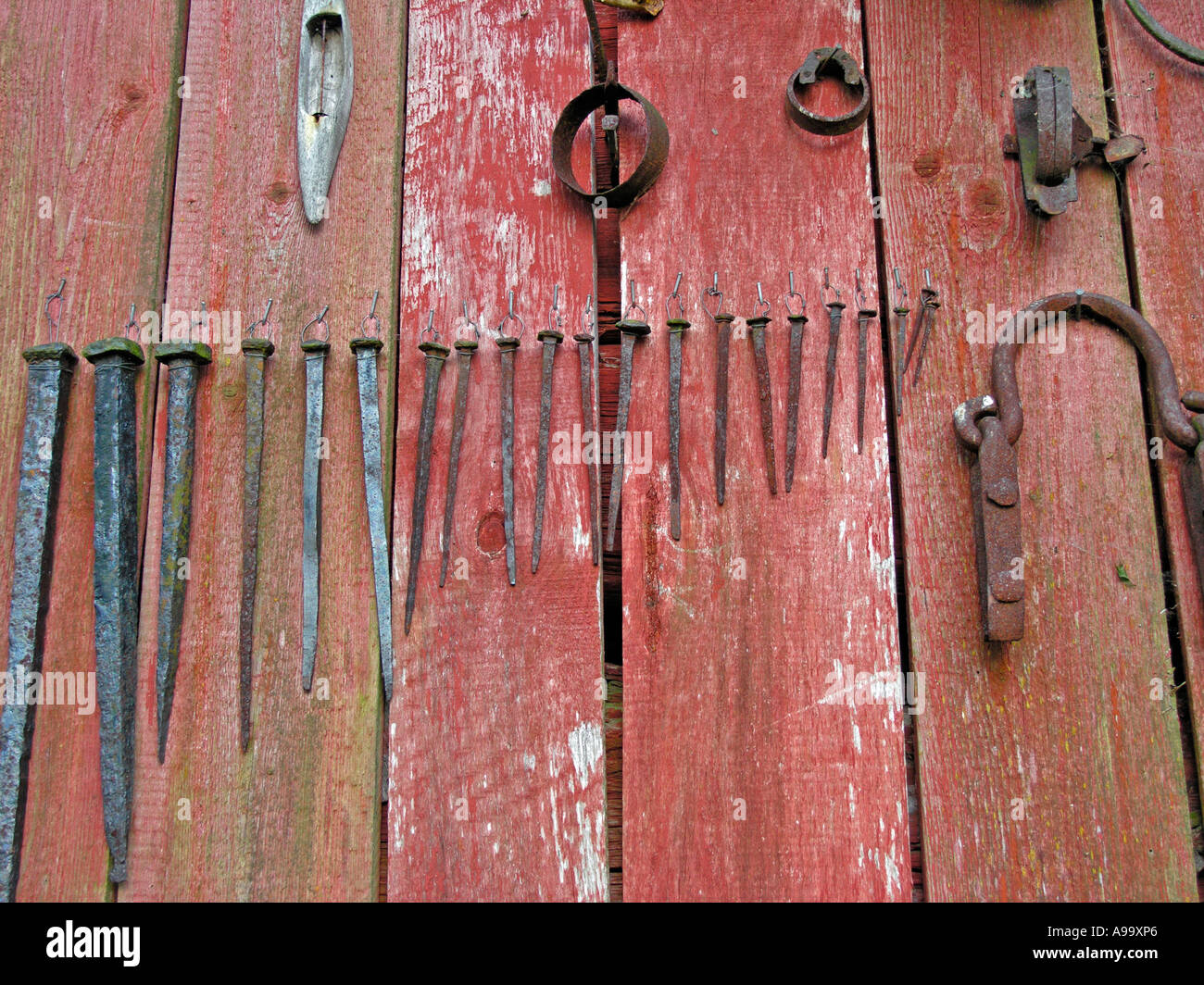 old iron tools and nails on wall of a red blockhouse log house Stock ...