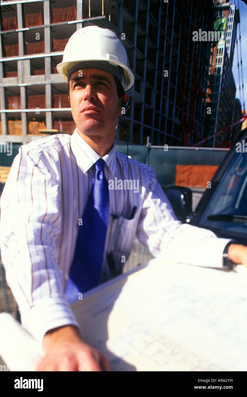 CONSTRUCTION MANAGER OUTDOORS AT BUILDING SITE WITH BLUEPRINTS Stock ...