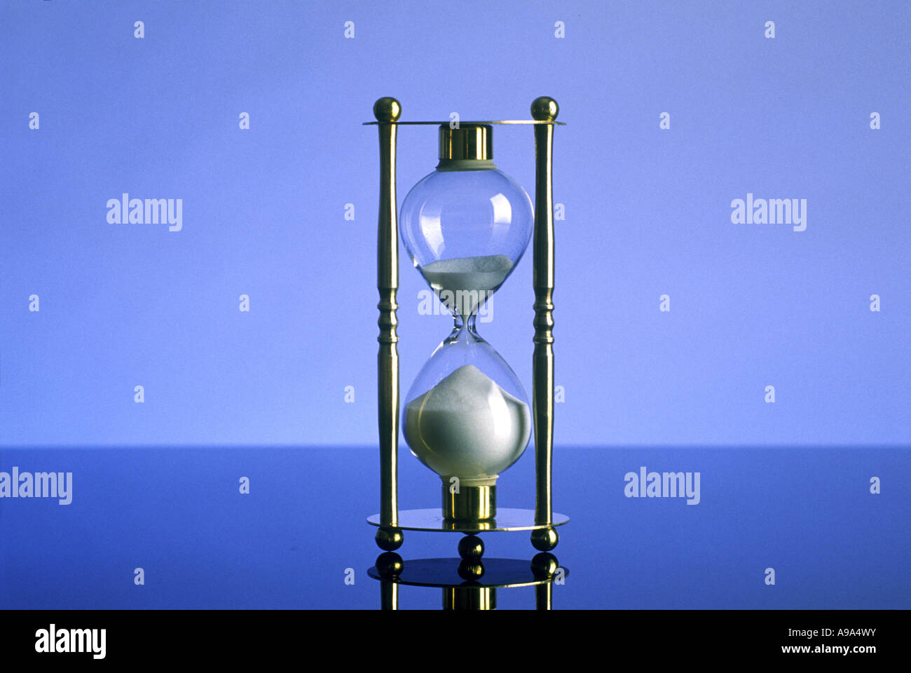 SAND FALLING THROUGH BRASS HOURGLASS SAND TIMER ON LIGHT BLUE ...