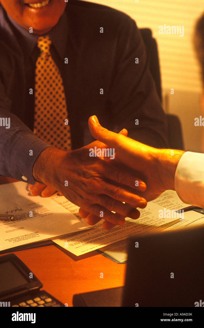 OFFICE WORKERS SHAKE HANDS AT DESK IN OFFICE Stock Photo - Alamy