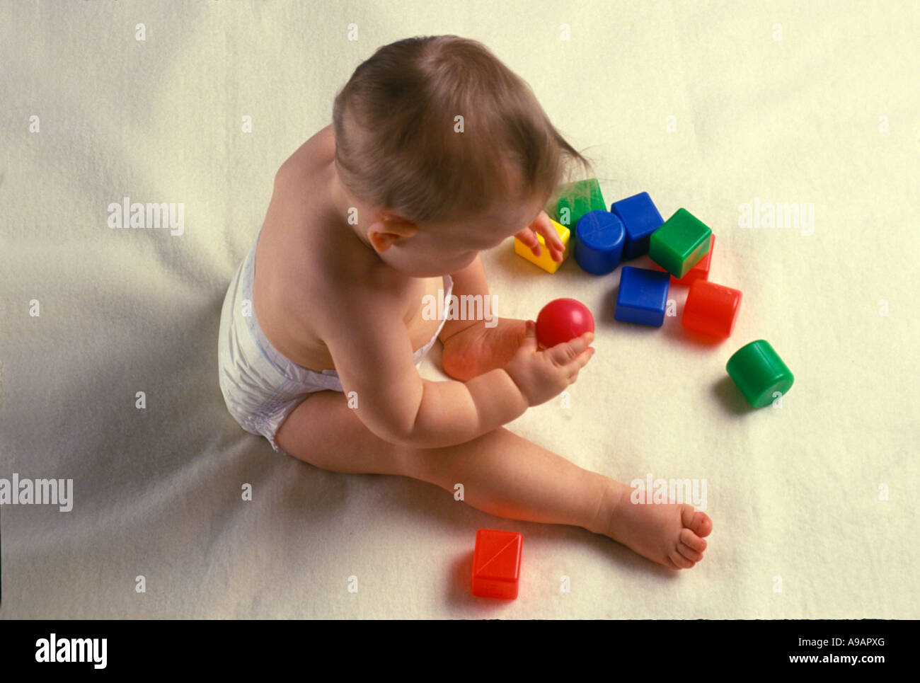 INFANT BABY PLAYING WITH COLORED TOY BUILDING BLOCKS Stock Photo - Alamy