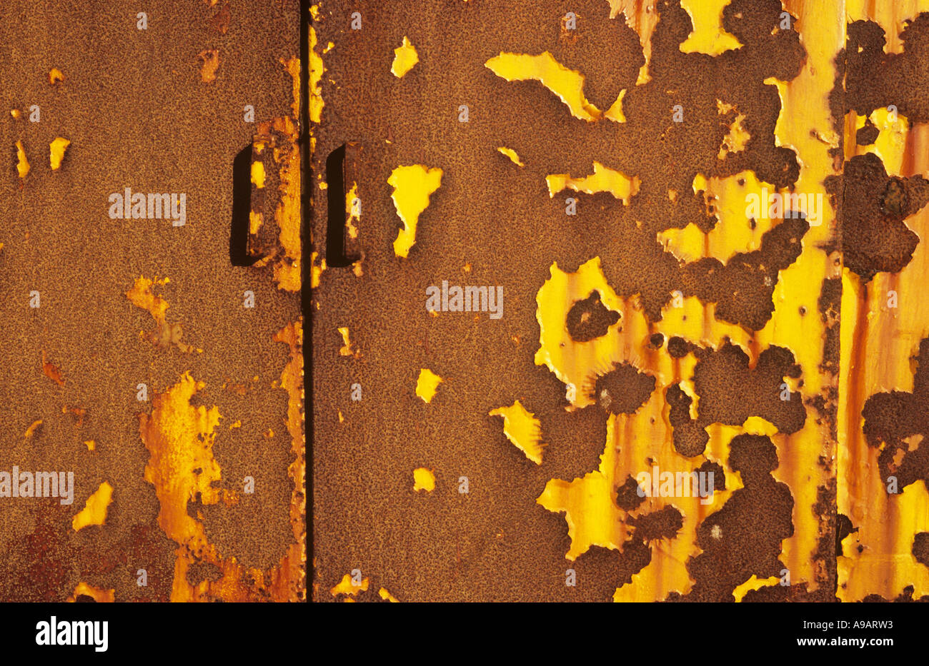 Detail of a yellow painted rusting metal cabinet or cupboard from which ...
