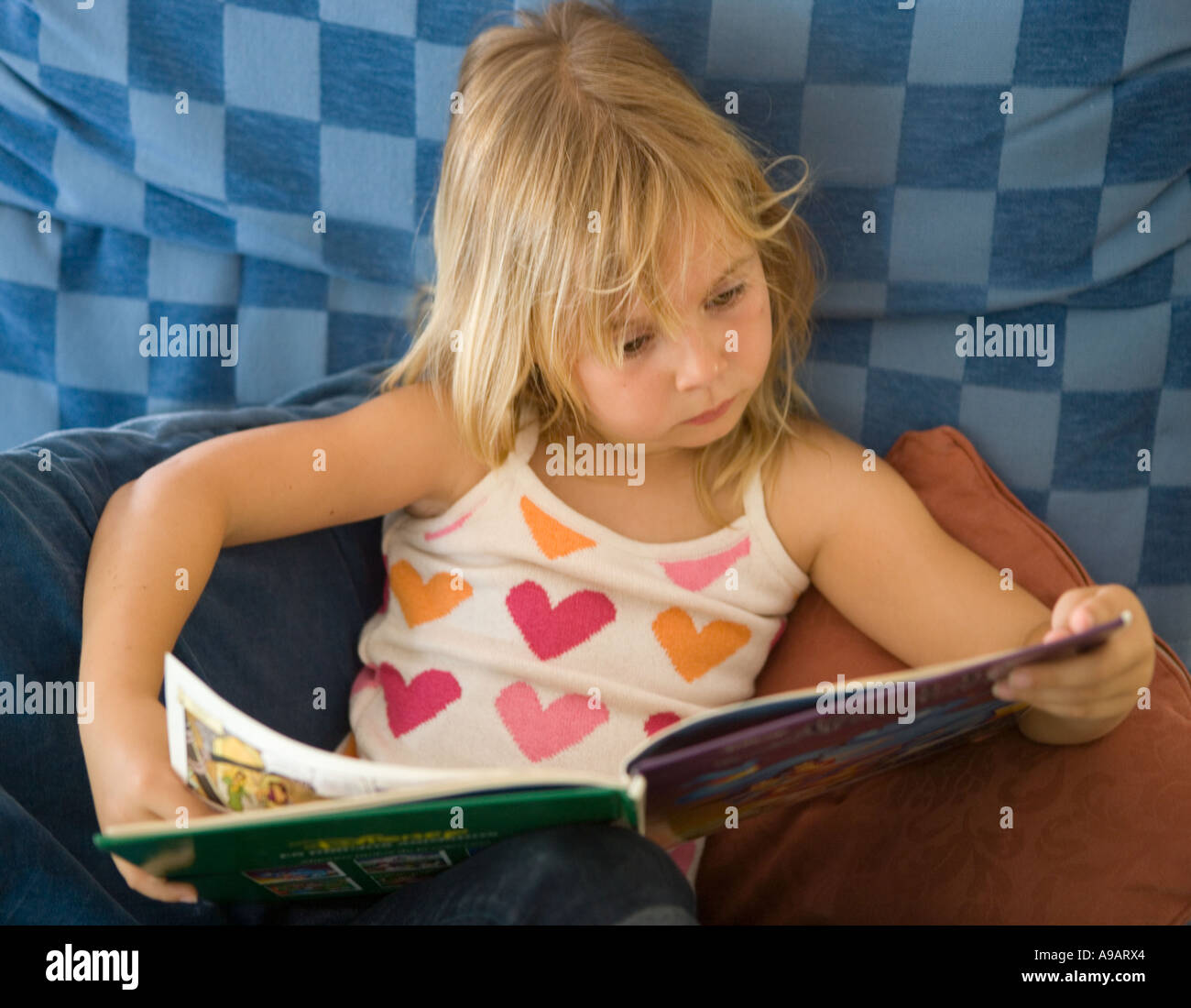 Six year old girl concentrating on reading Stock Photo - Alamy