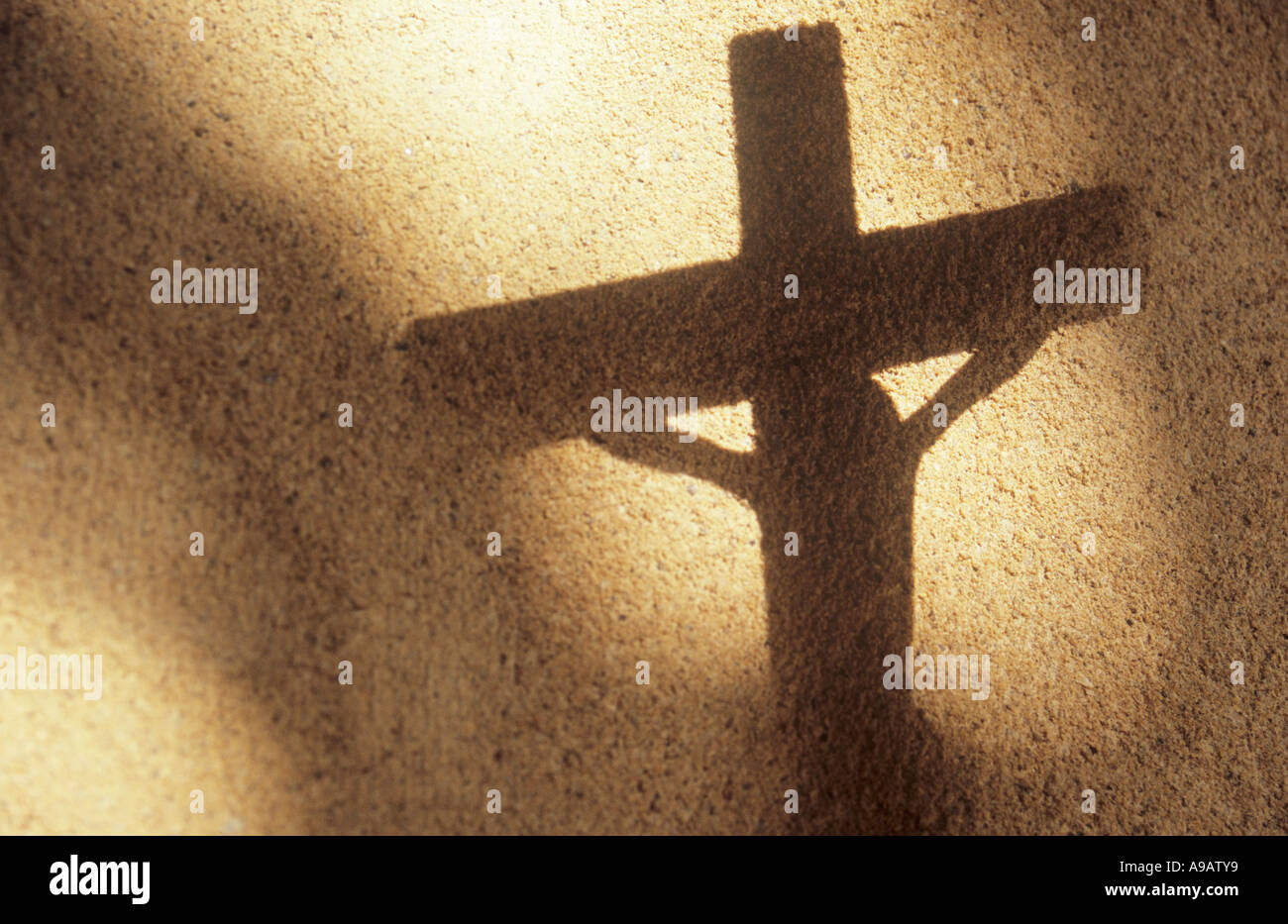 A shadow against a pale rendered wall of Jesus Christ hanging from a ...