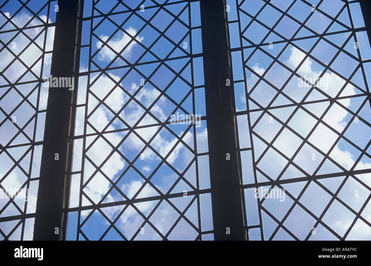 View through diamond leaded window panes to a blue sky with white ...