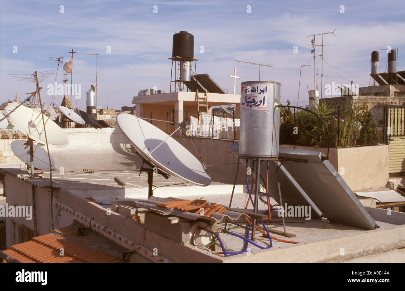 view across rooftops showing solar water heaters and satellite dishes ...