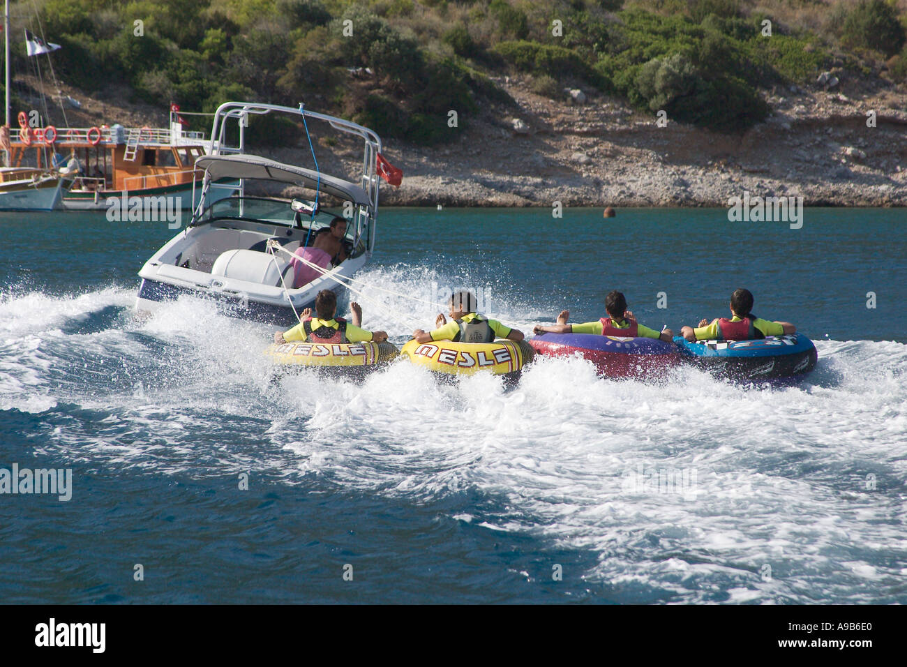 Four teenagers being pulled on inflatable donuts by speed boat Stock ...