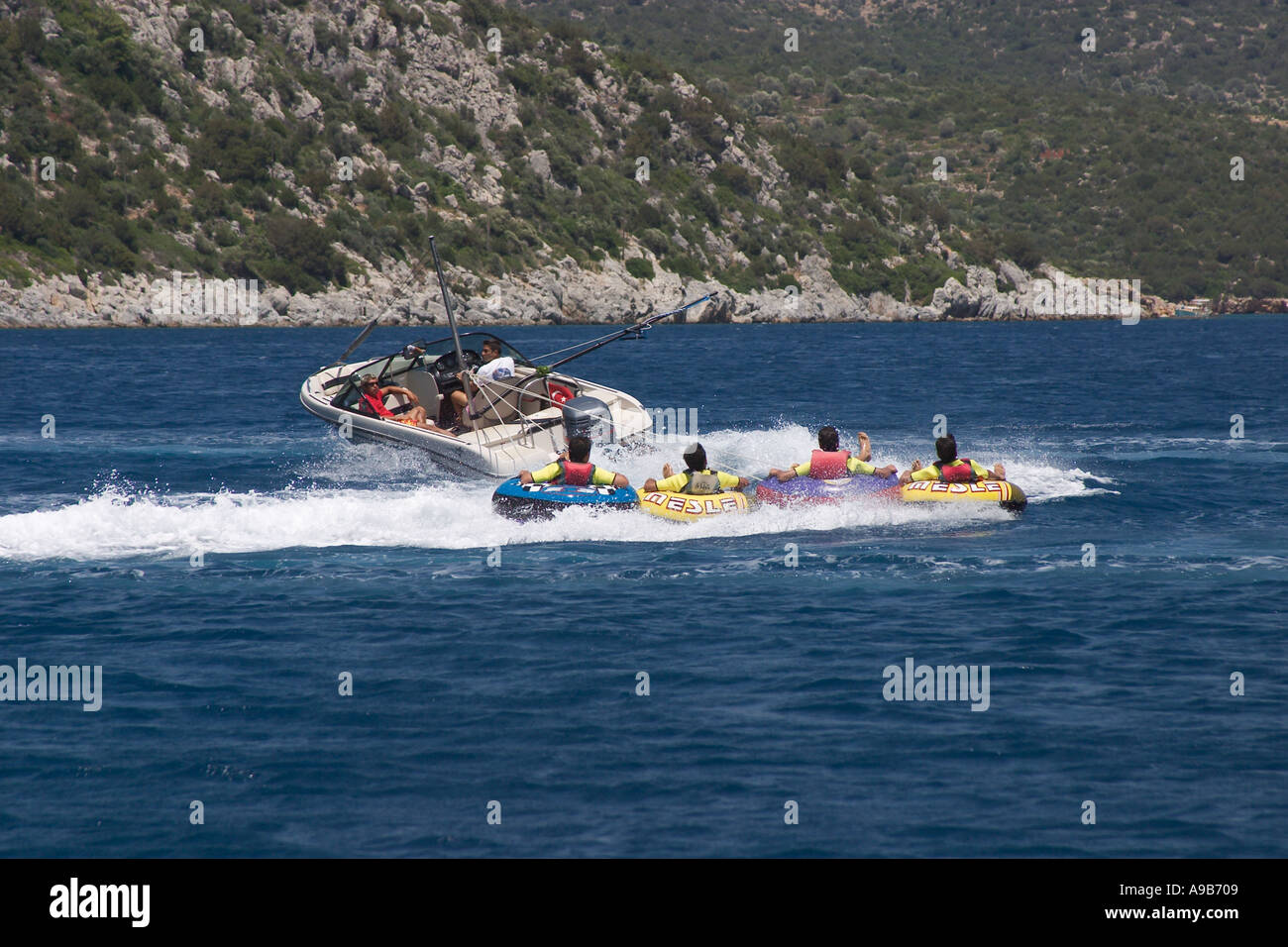 Four teenagers being pulled on inflatable donuts by speed boat Stock ...