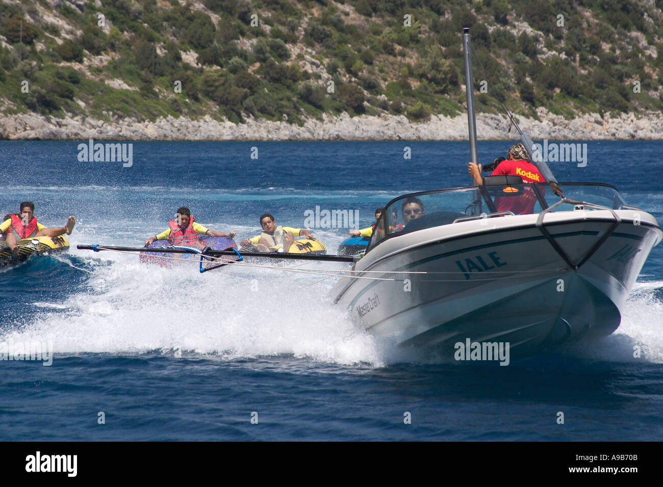 Four teenagers being pulled on inflatable donuts by speed boat Stock ...