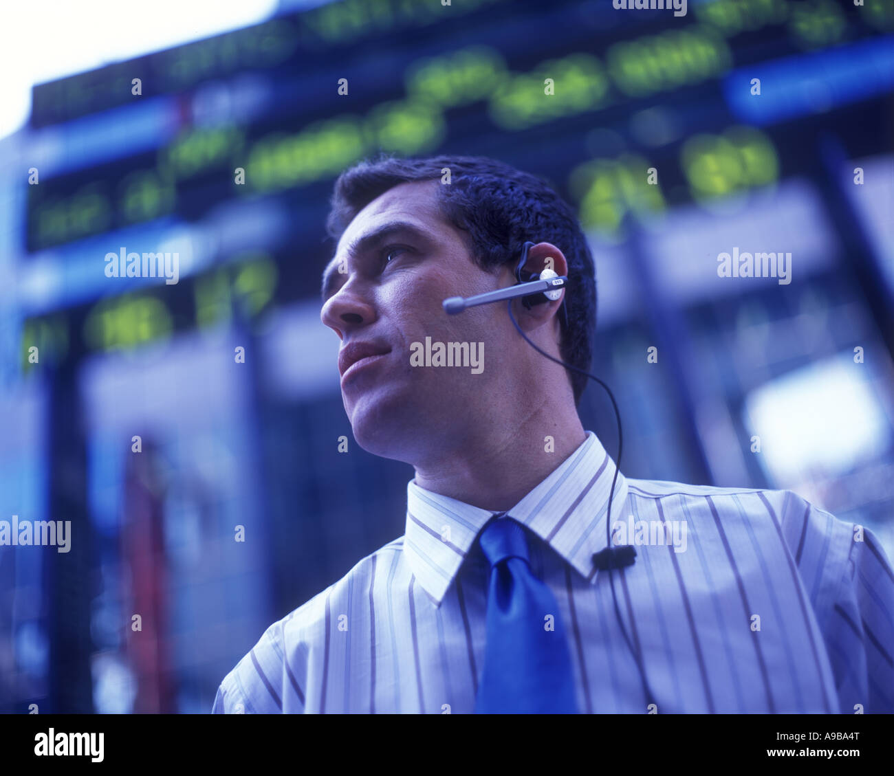 HAPPY SMILING OFFICE WORKER LOOKING UP STANDING BY STOCK MARKET TICKER ...