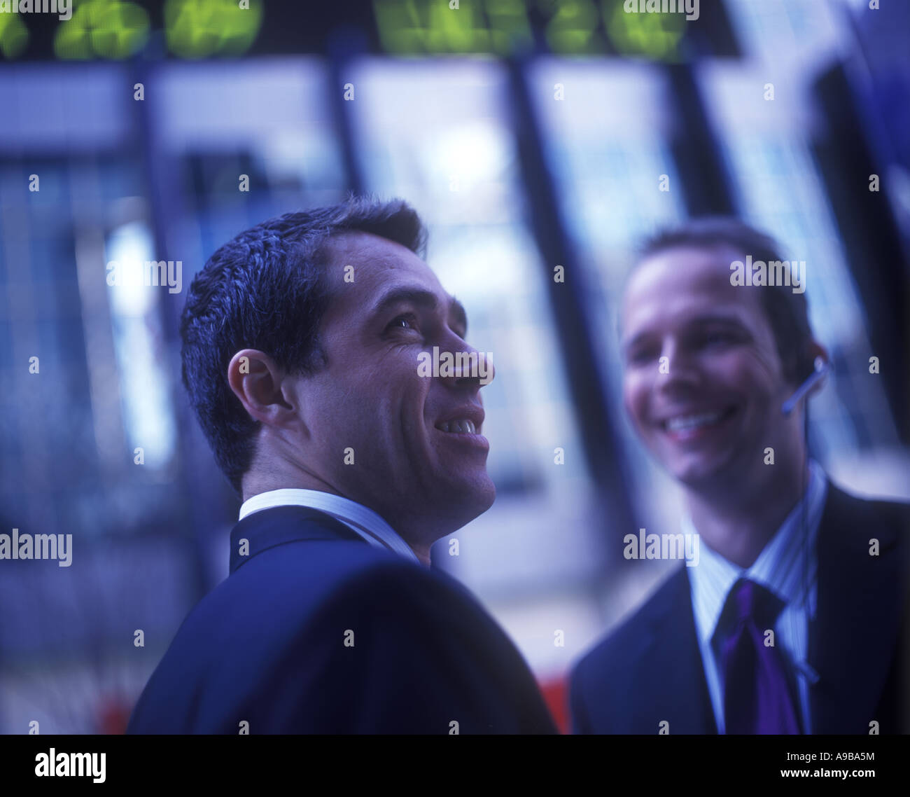 SMILING HAPPY OFFICE WORKERS STANDING BY STOCK MARKET TICKER DISPLAY ...