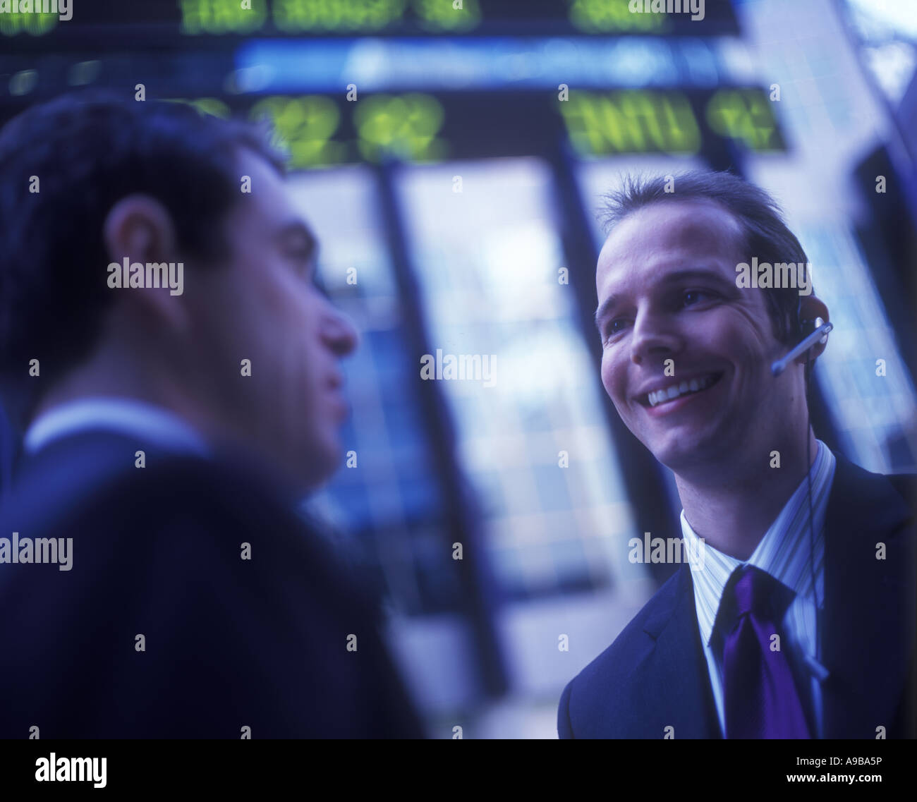 SMILING HAPPY OFFICE WORKERS STANDING BY STOCK MARKET TICKER DISPLAY ...