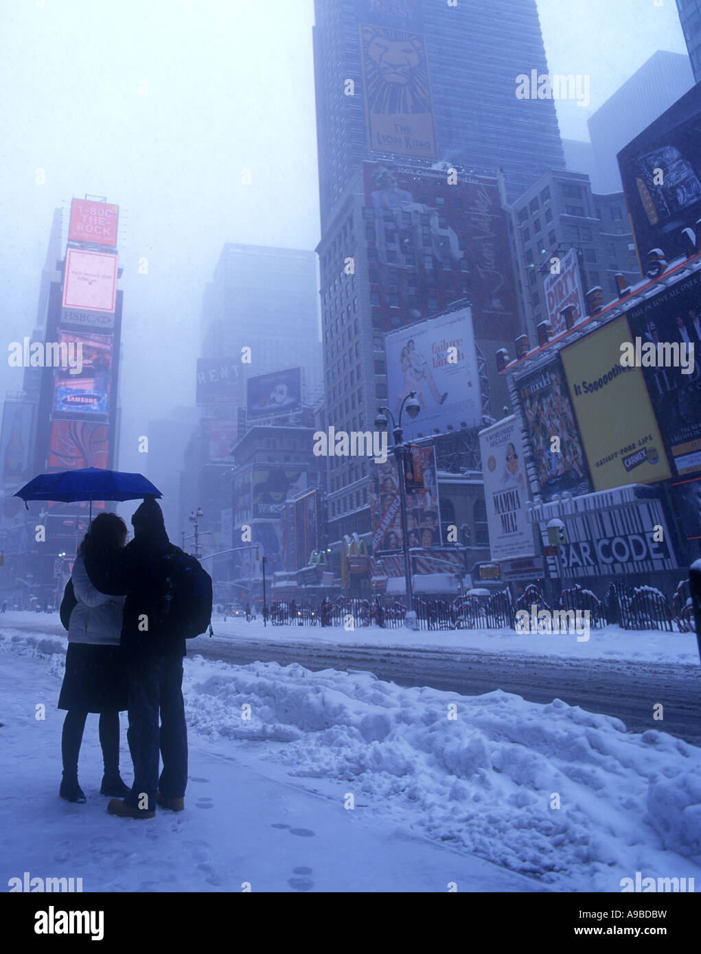 YOUNG COUPLE STANDING IN SNOW COVERED BLIZZARD TIMES SQUARE MIDTOWN ...