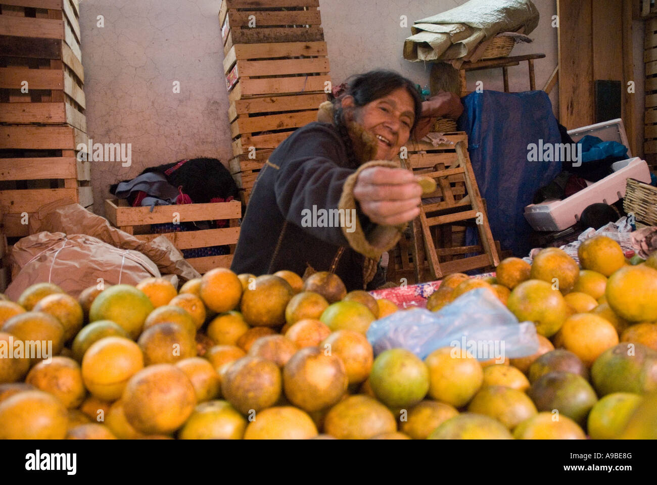 indigenous woman sell orange and give the rest to someone in the market ...