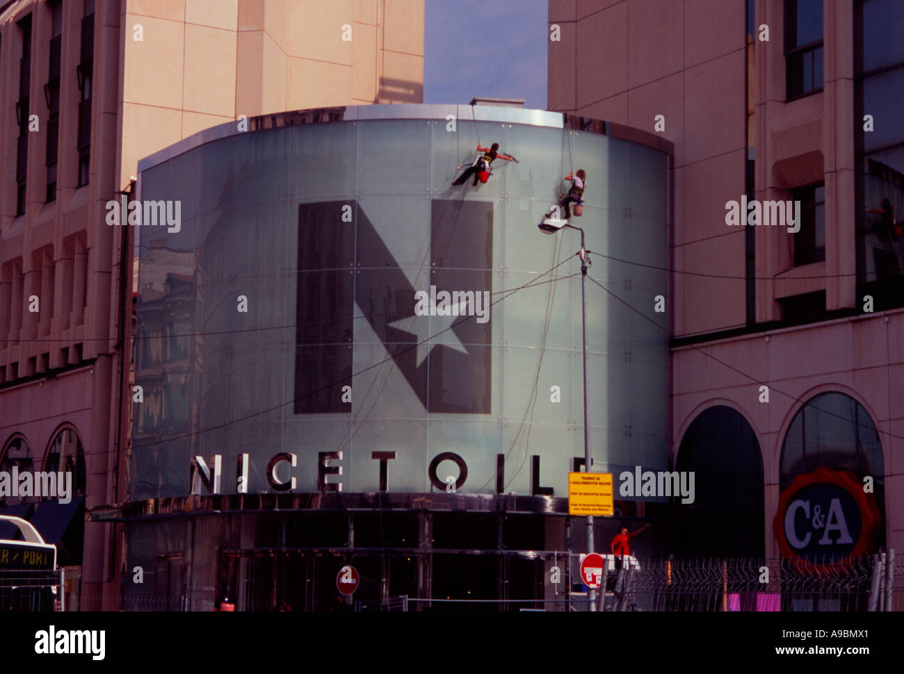 Window cleaners cleaning the glass windows of a large department store ...