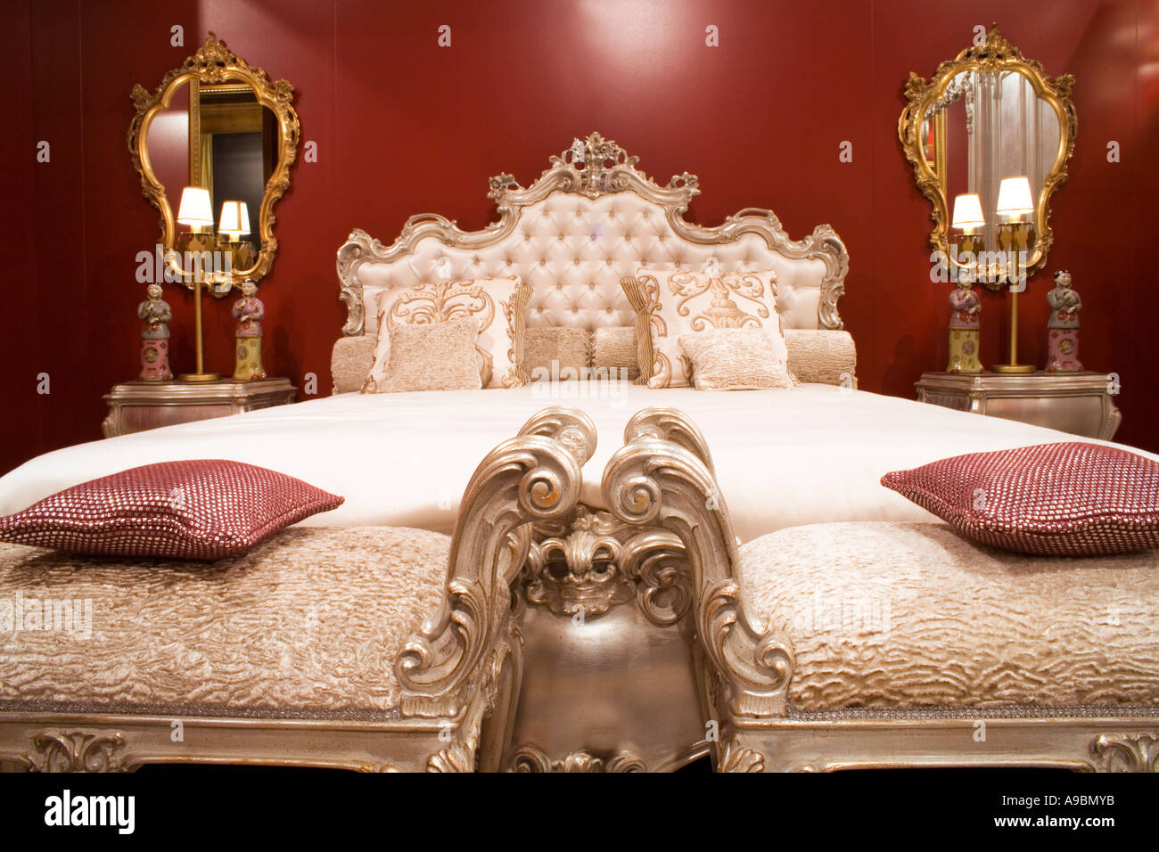 Silver finished capitonè bed with dormeuses at its feet in red wall ...