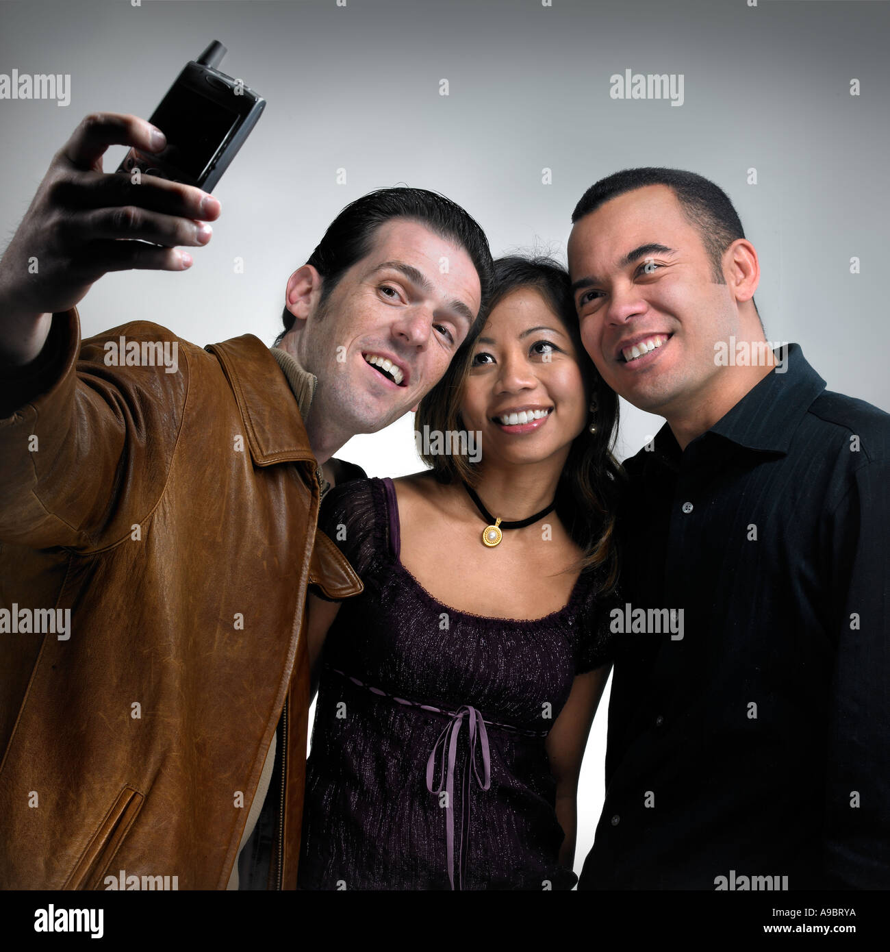 A group of diverse friends pose for a self portrait with a camera phone ...