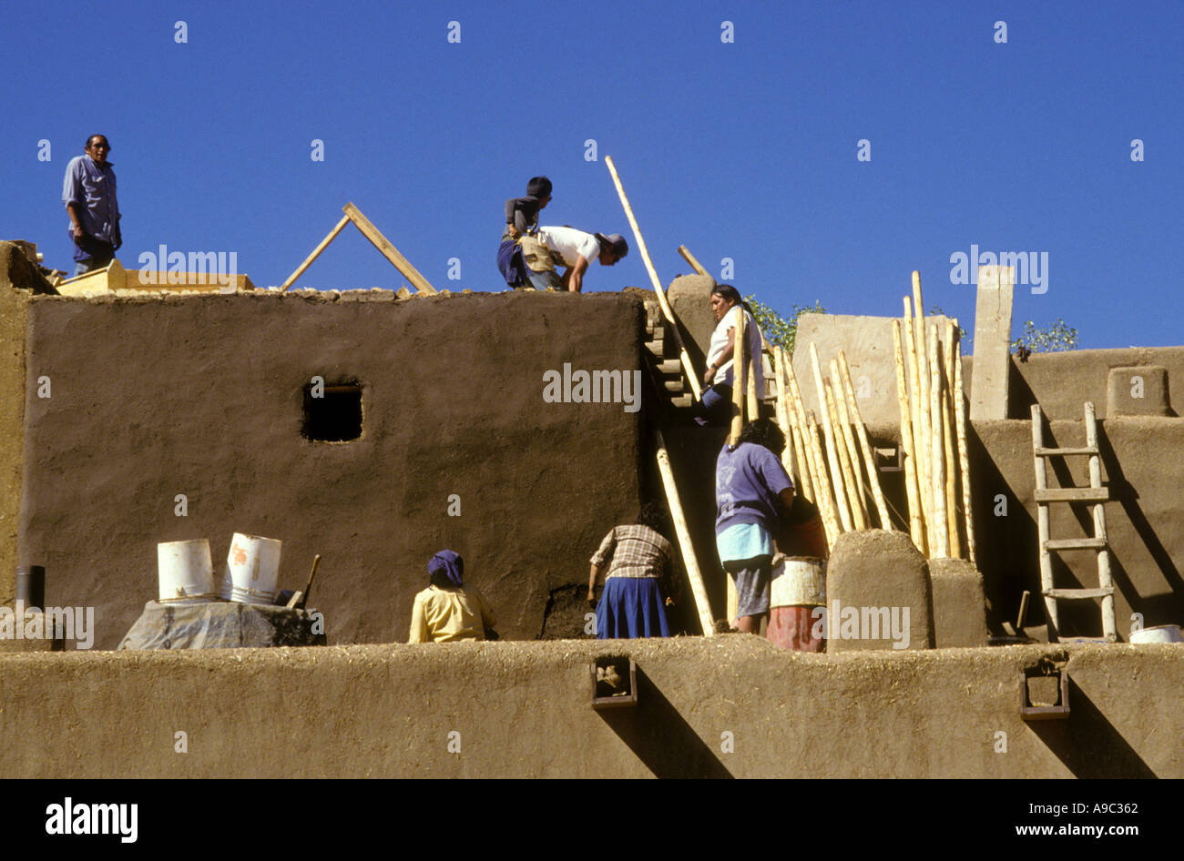 New Mexico Taos Taos Pueblo native americans working on adobe building ...