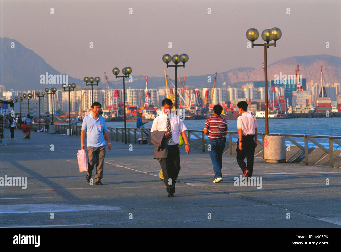 People walking on the promenade in kowloon harbour view of causeway bay ...